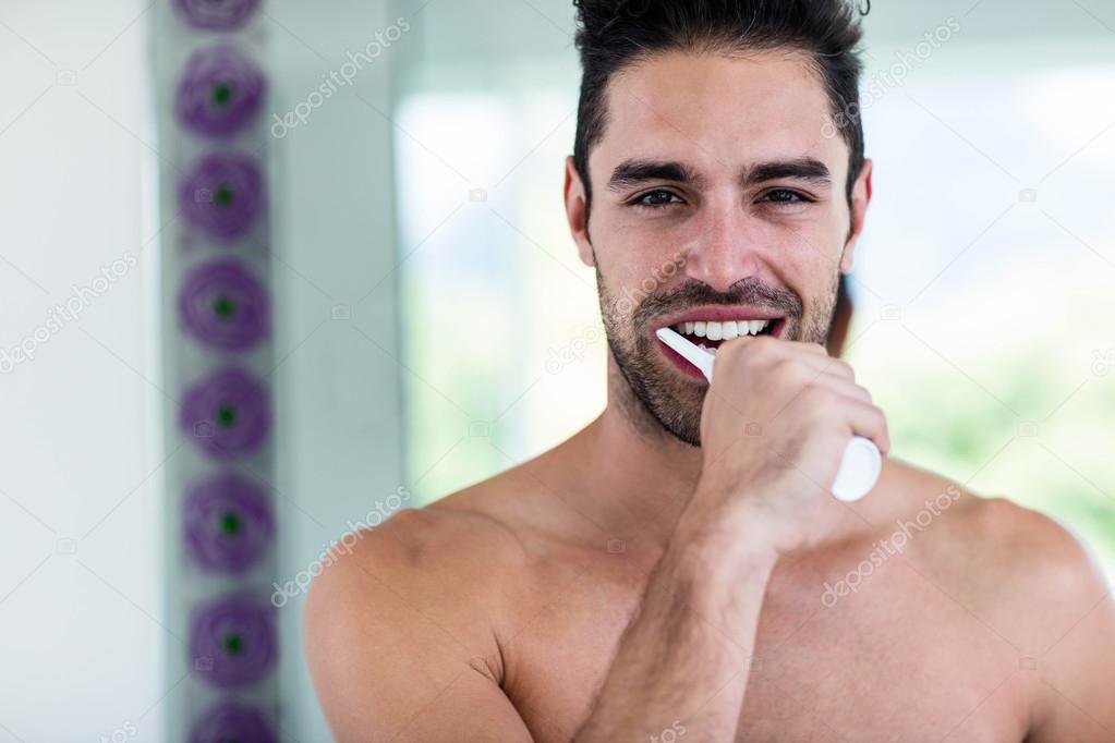 Handsome man brushing his teeth Stock Photo by ©Wavebreakmedia 98069072