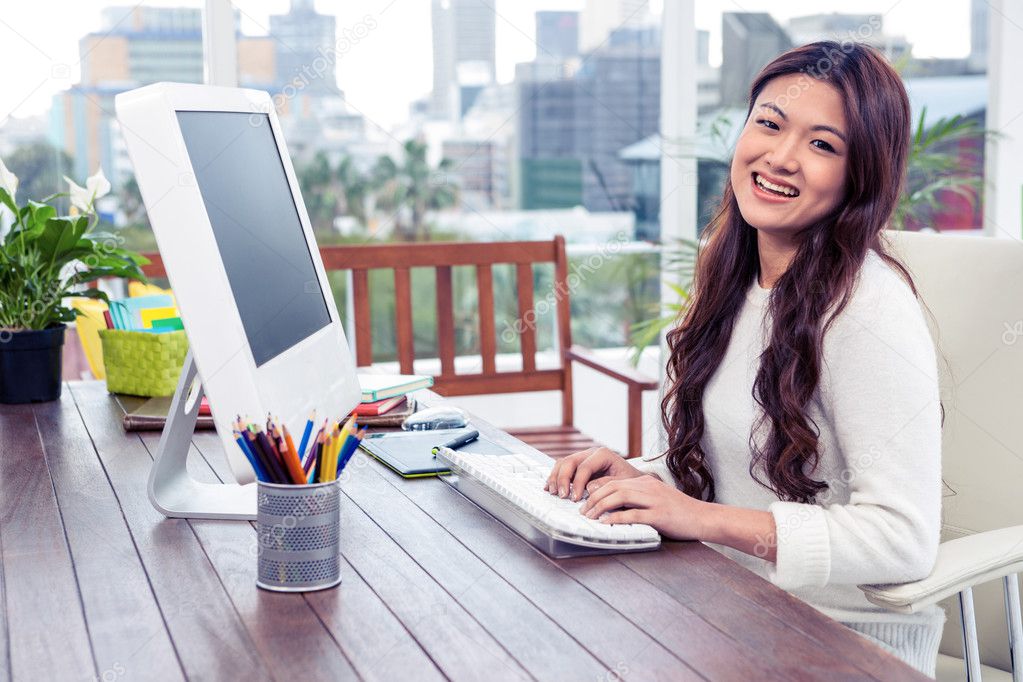 Smiling Asian woman using computer — Stock Photo © Wavebreakmedia #98094610