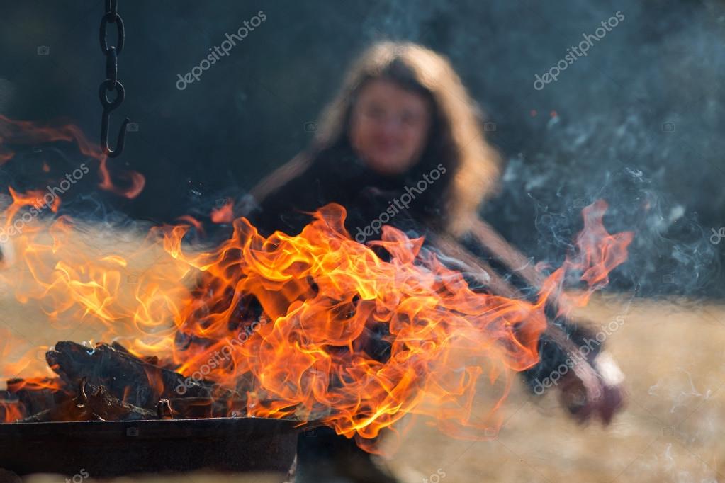 Fire flames on a grill with woman in background relaxing Stock Photo by ...