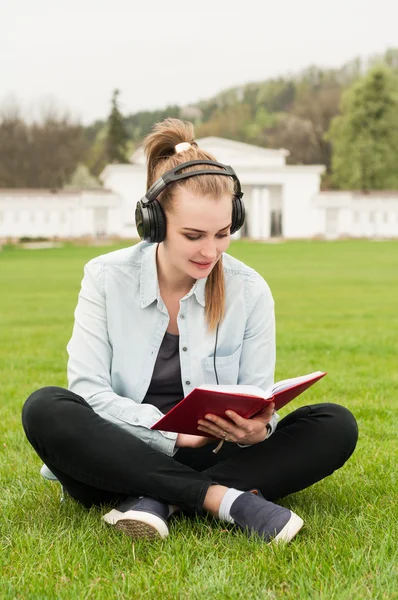 Portrait of joyful female reading a book while listening music - Stock ...