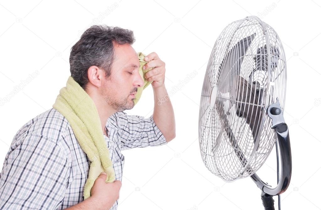 Man wiping sweaty forehead in front of cooling fan — Stock Photo ...