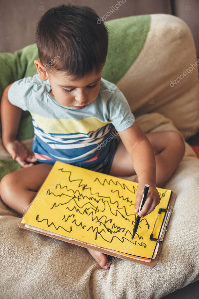 Lindo chico caucásico está dibujando algo en un papel amarillo con un ...