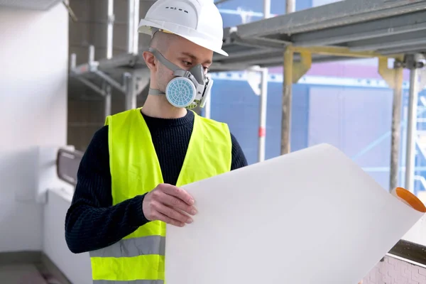 young male builder foreman, architect in hardhat, protective respirator ...