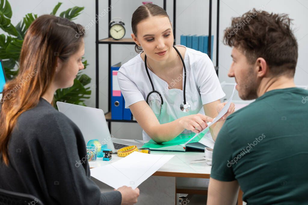 Un ginec logo est explicando los resultados de las pruebas a una paciente embarazada. Una pareja ...