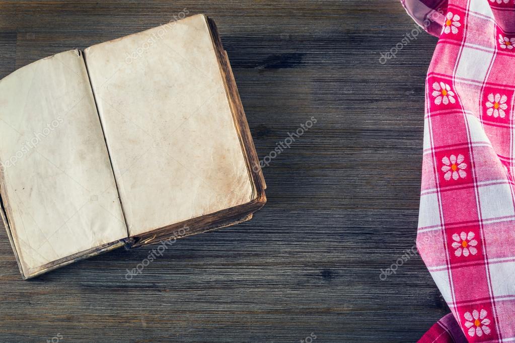 Old open book on a wooden table and loosely laid kitchen napkin Stock ...