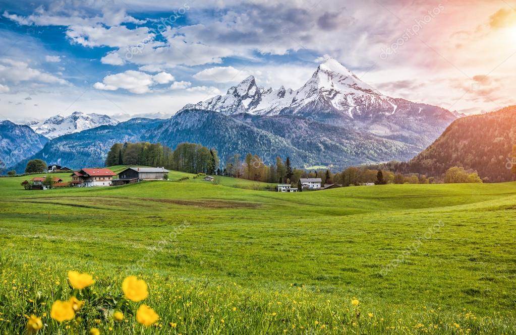 Idyllic alpine landscape with green meadows, farmhouses and snowcapped ...