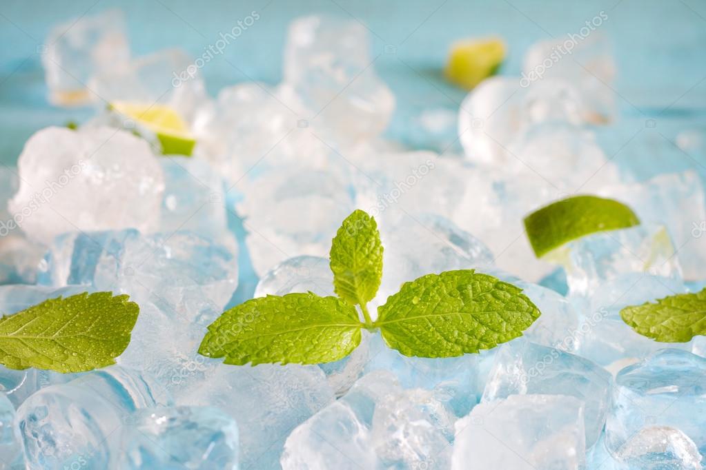 Ice cubes and fresh mint leaves abstract background on blue boards ...