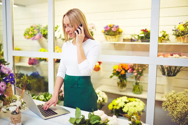 Florist speaking on phone in flower shop - Stock Image - Everypixel