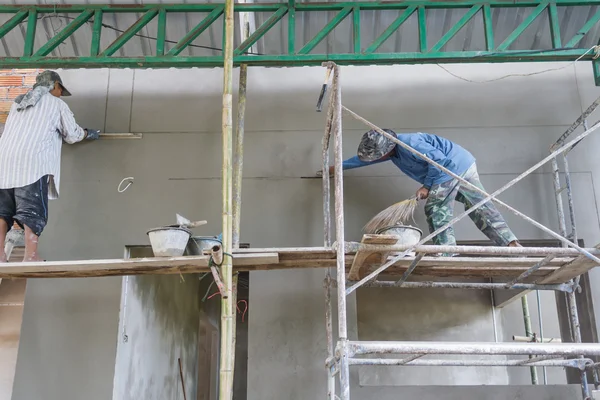Construction workers plastering building wall and beam using cement ...