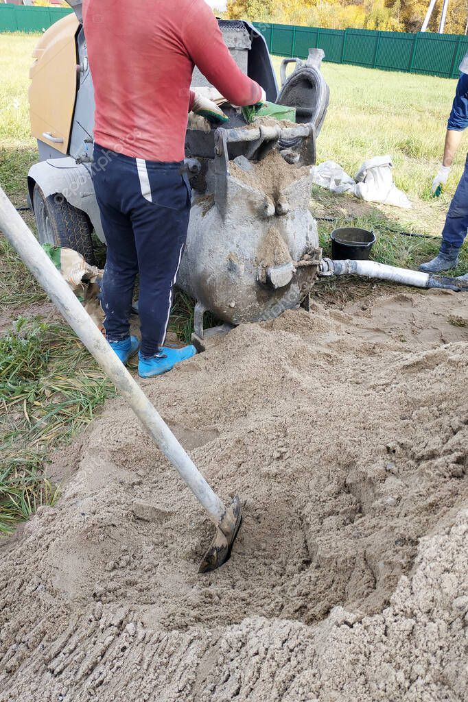 El trabajador mezcla cemento con arena en una hormigonera. 2020 2022