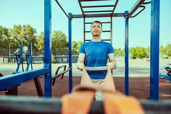 Working out at outdoor gym. Handsome muscular man does strength ...