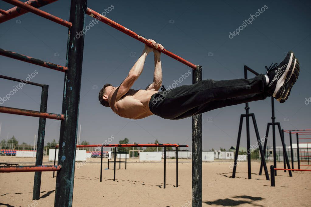 joven haciendo ejercicio abdominal en barra horizontal en el parque de ...