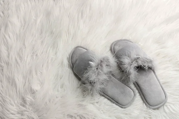 Pair of soft slippers on white faux fur, flat lay. Space for text ...
