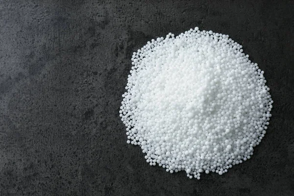 Pellets de nitrato de amonio sobre mesa gris, plano yac a con espacio para el texto. Abono ...