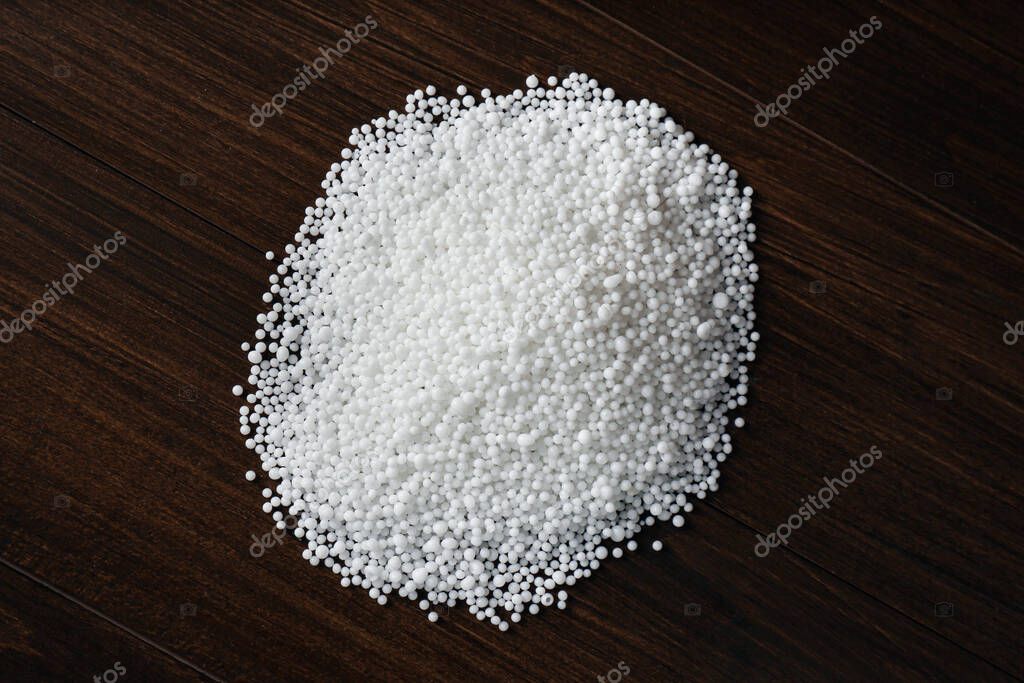 Pellets de nitrato de amonio sobre mesa de madera, puesta plana. Abono mineral 2022