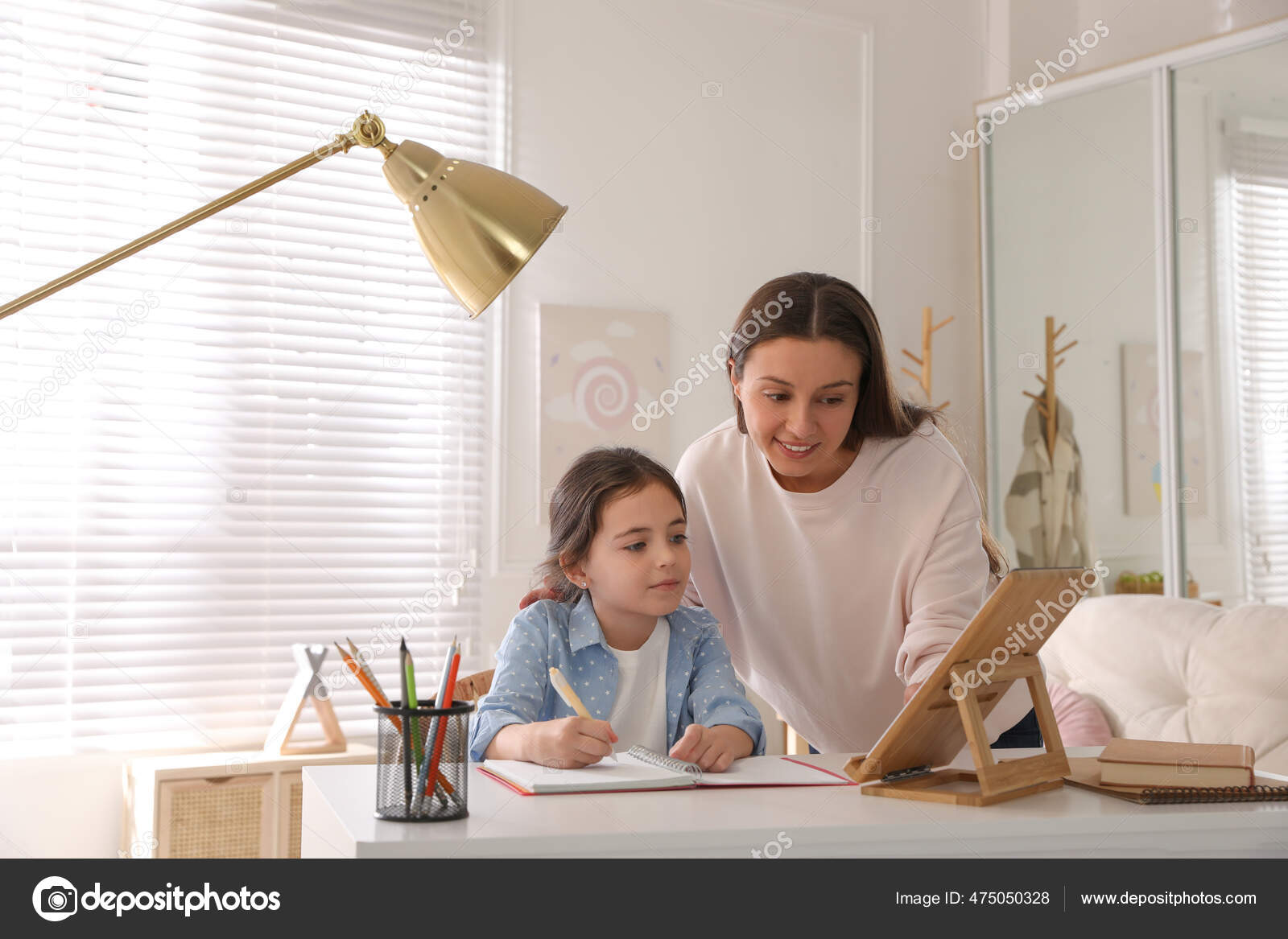 Mother Helping Her Daughter Homework Using Tablet Home Stock Photo by ©NewAfrica 475050328
