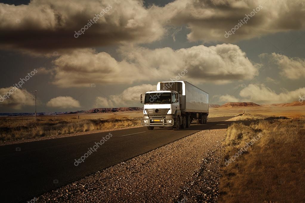 Truck traveling on a road in the desert at sunset — Stock Photo ...