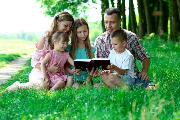 young happy family reading the Bible in nature - Stock Image - Everypixel