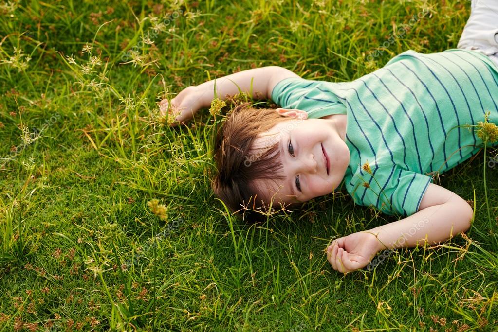Boy lying in green grass Stock Photo by ©DragonImages 104954330