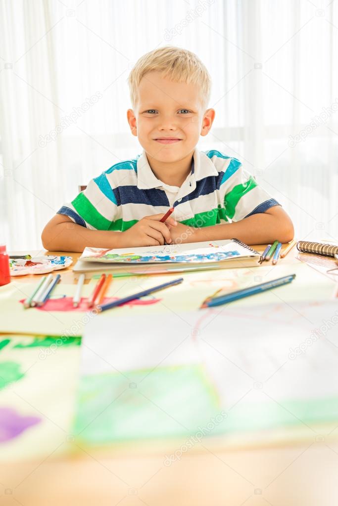 Smiling boy drawing with pencils Stock Photo by ©DragonImages 56937775