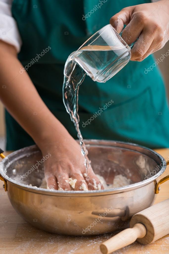 Hands pouring water into the bowl with flour — Stock Photo ...