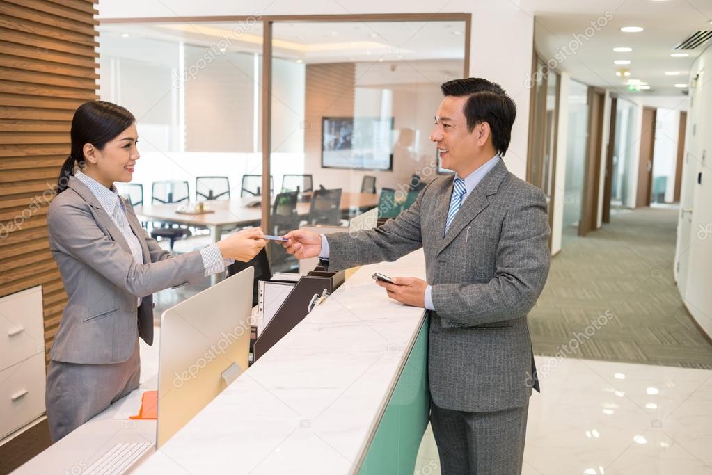 Receptionist giving card to the businessman Stock Photo by ...