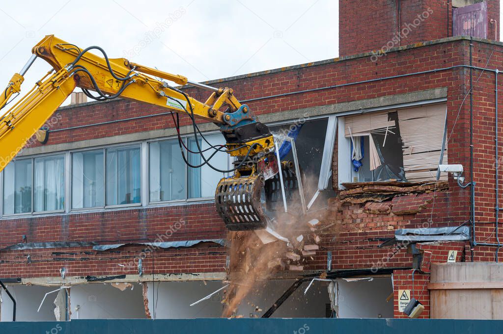 Demolición de un edificio antiguo con una mandíbula hidráulica de larga ...
