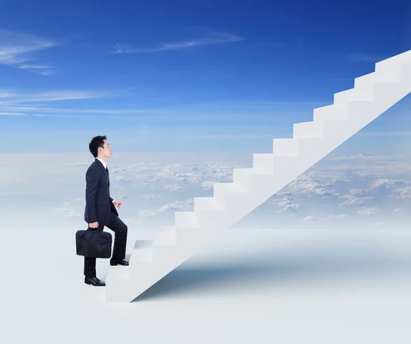 Business man stepping up on stairs with cloud and sky background ...