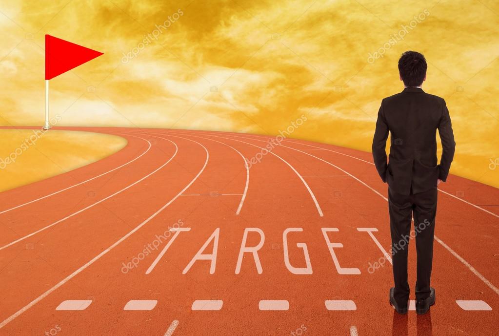 hombre de negocios de pie en pista de atletismo y mirando a la meta 2024