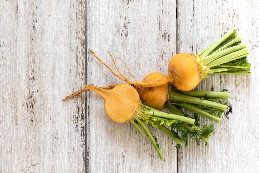 Rebanada de nabo amarillo con hojas sobre un fondo de madera blanca ...