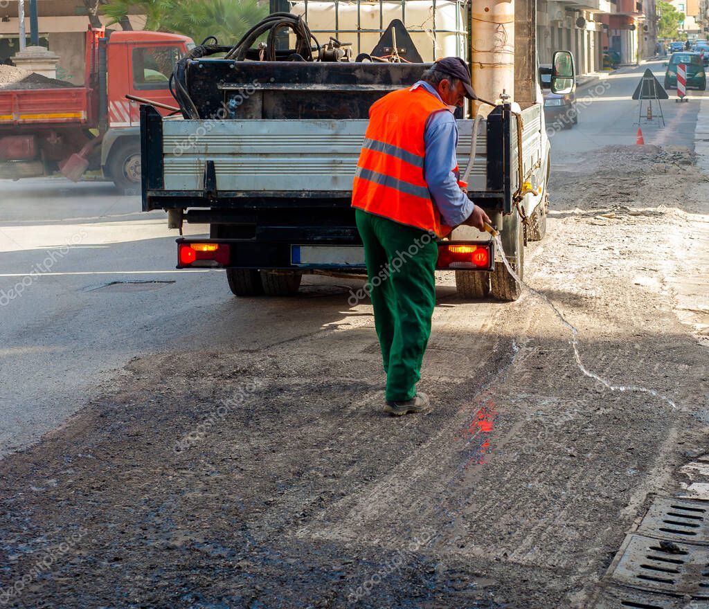 trabajador vierte agua en el asfalto molido para los trabajos de ...