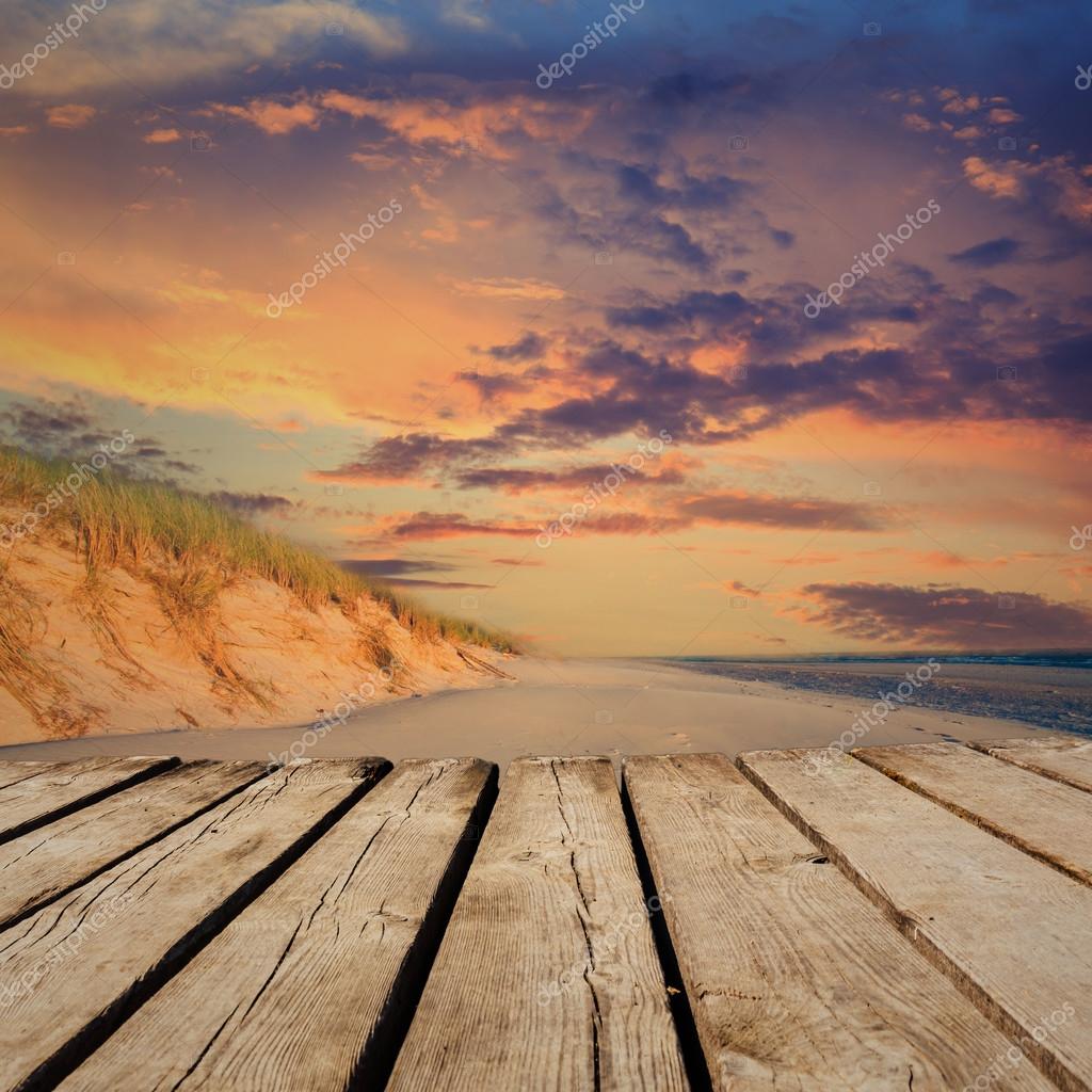 Sunset on the beach and empty wooden deck table. Ready for product ...