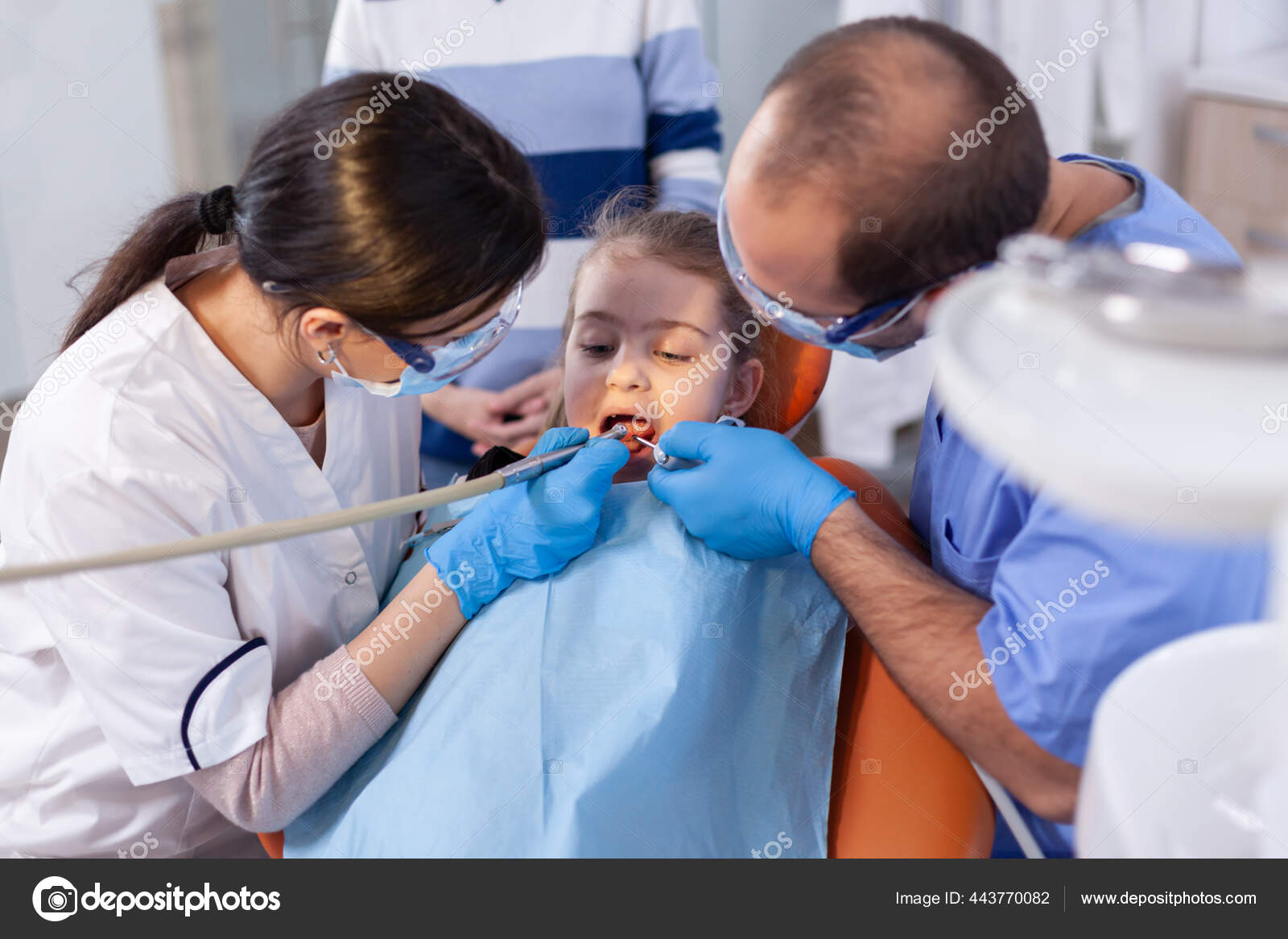 Dentist and assistant using instruments during dental treatment for ...