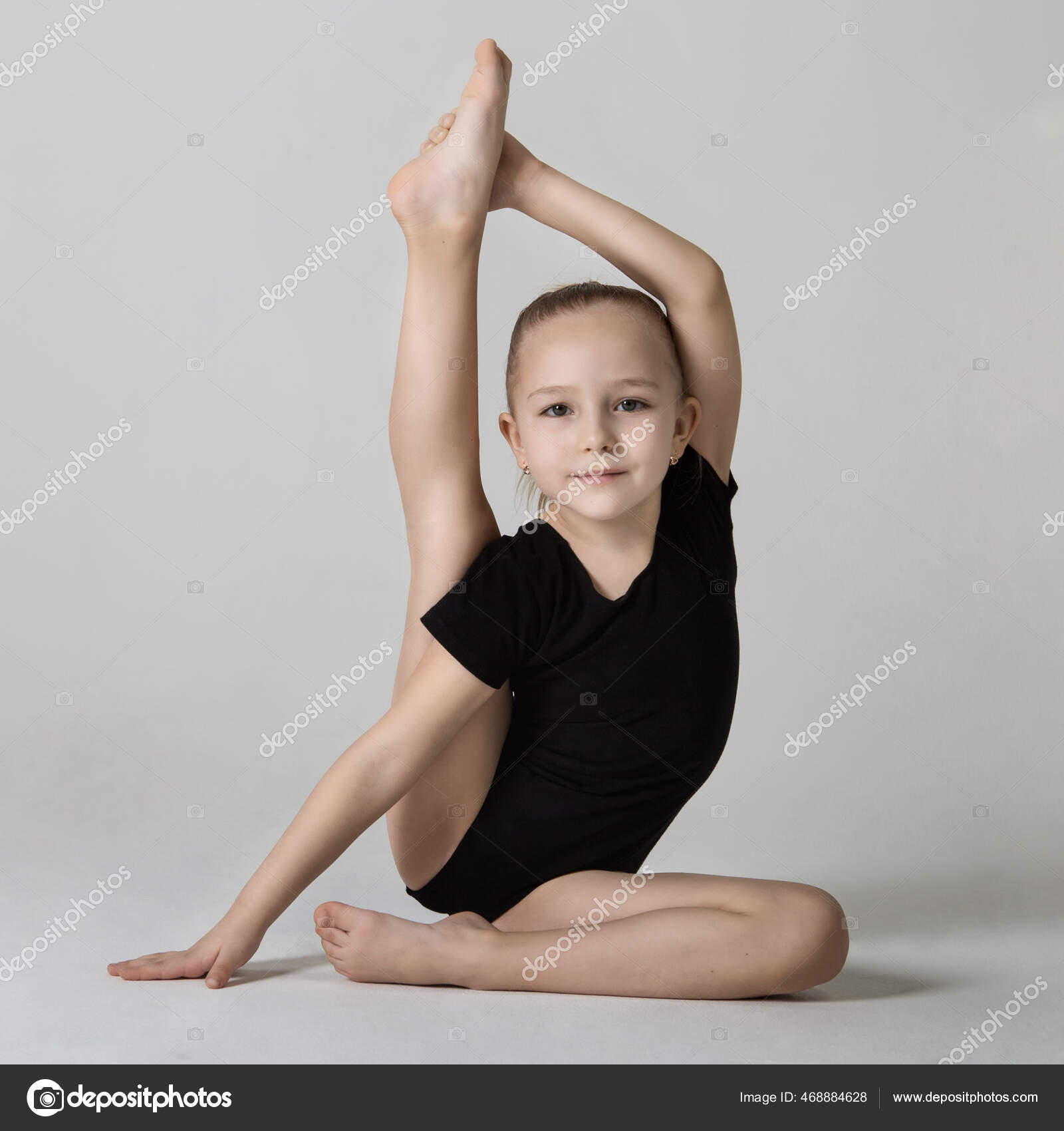 Little gymnast demonstrates flexibility and balance in a gymnastic pose ...