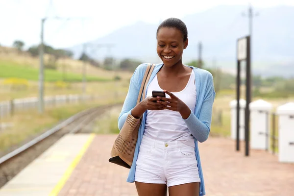 Woman using mobile phone at railway station - Stock Image - Everypixel