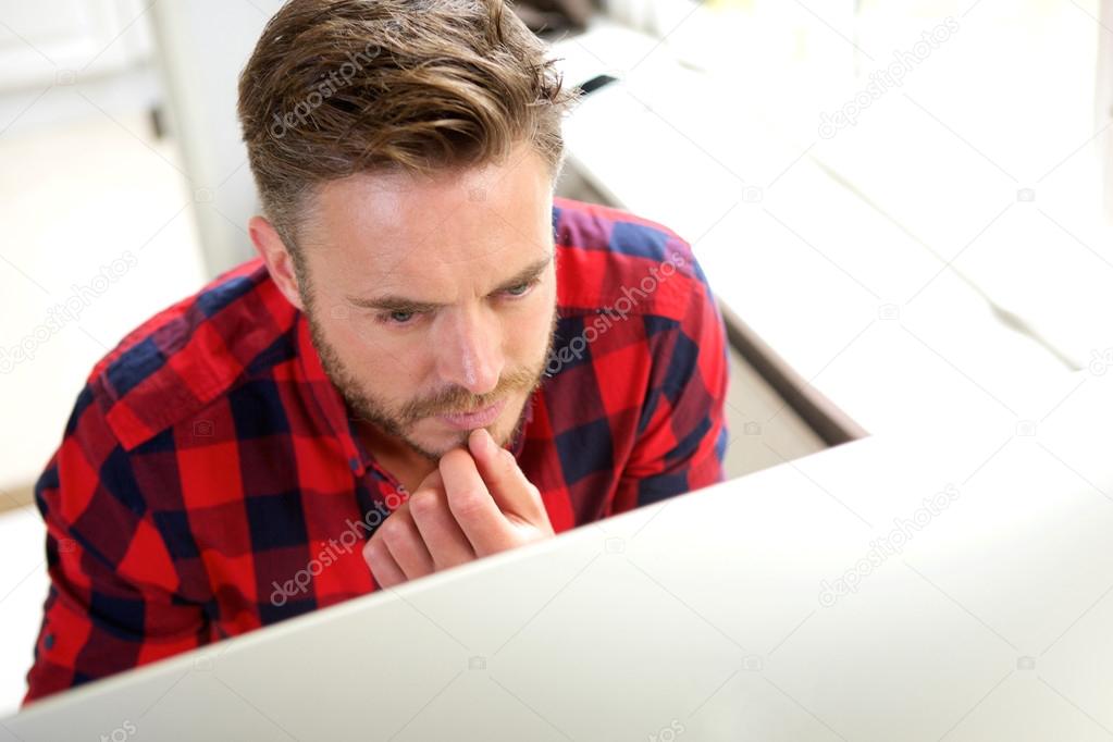 Attractive business man thinking behind computer screen Stock Photo by ...
