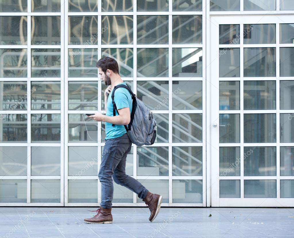 Male student walking on campus with bag and mobile phone ⬇ Stock Photo ...