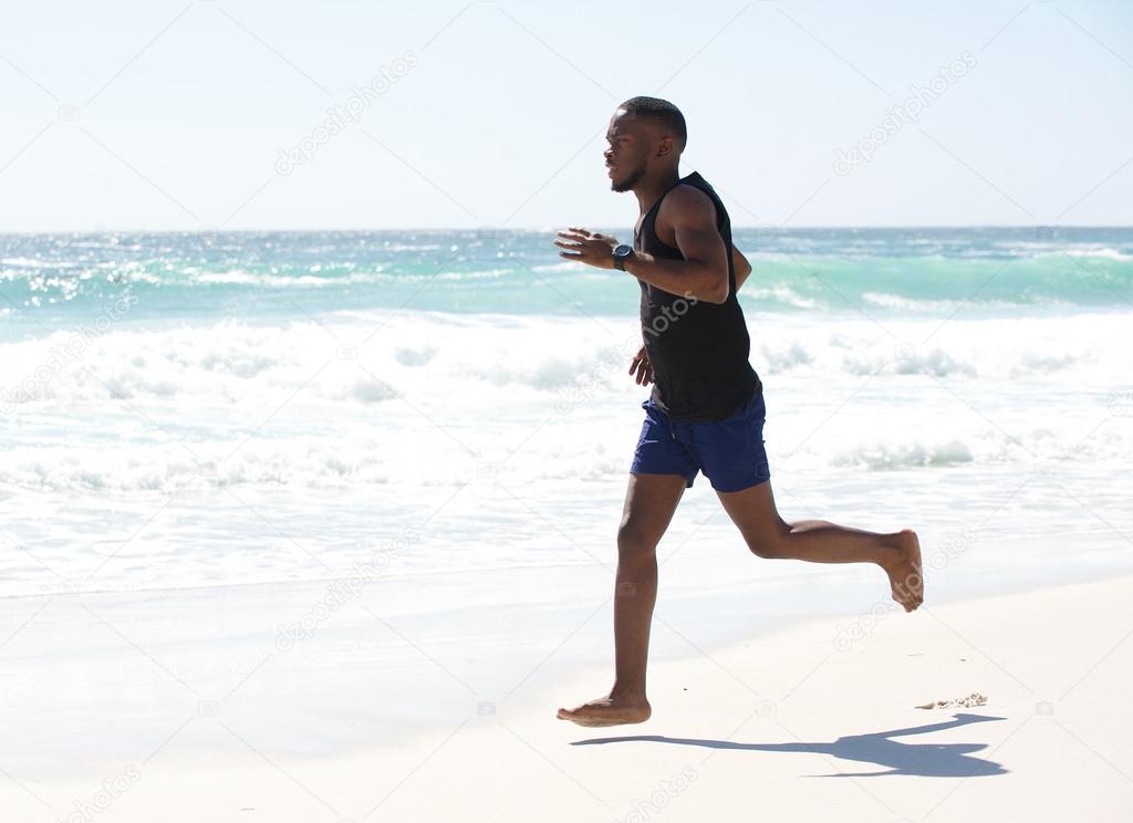 Young man running barefoot at the beach — Stock Photo © mimagephotos ...