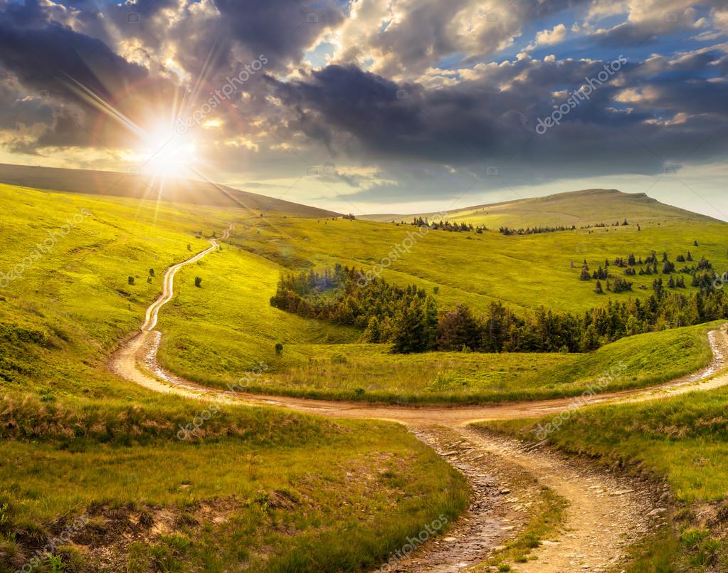 Cross road on hillside meadow in mountain at sunrise at sunset — Stock ...