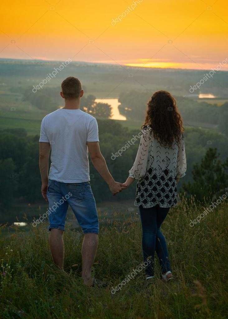 Romantic couple looking into the distance at sunset on outdoor ...