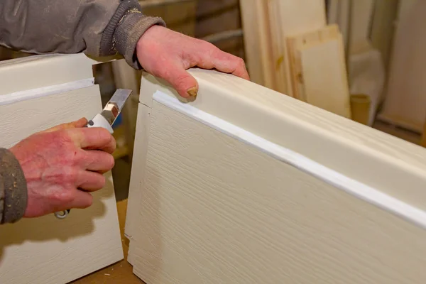 Carpentry worker is cutting rubber tape to facilitate putting together ...