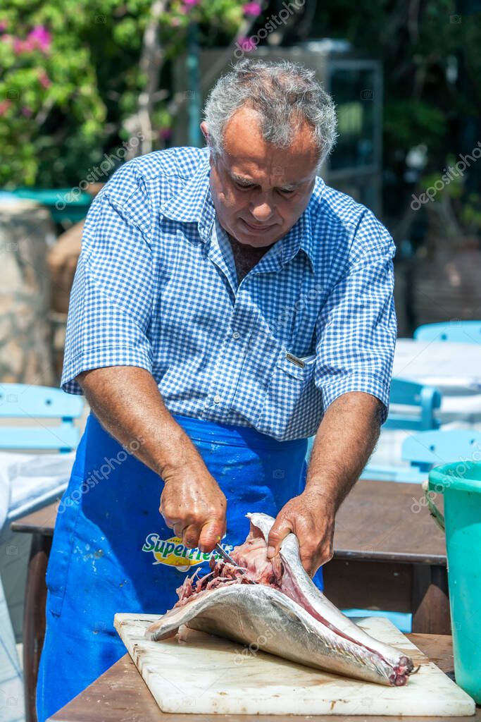Un pescadero filete un pescado recién capturado en una mesa adyacente ...