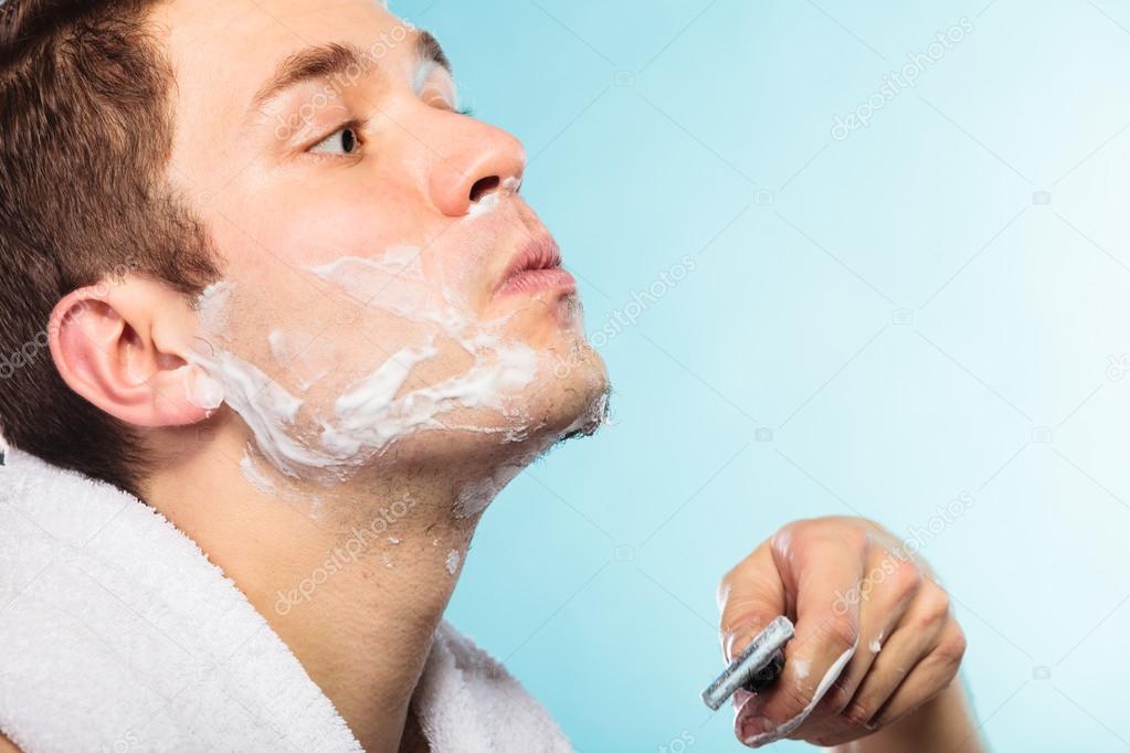 Young man shaving using razor with cream foam. Stock Photo by ©Voyagerix 114573618