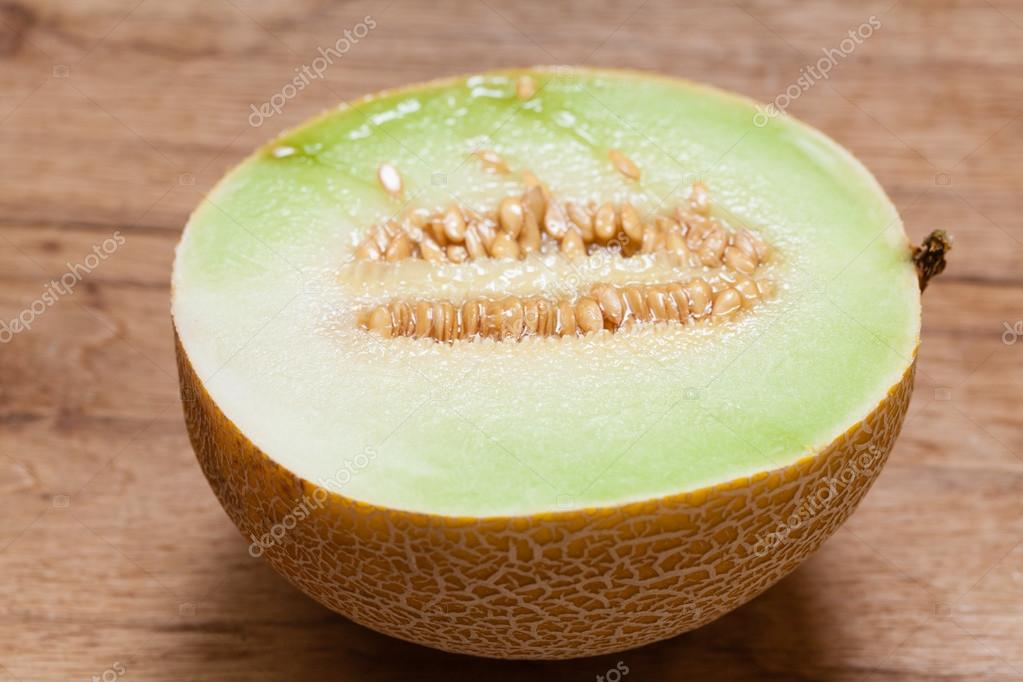 Melon with pips on wooden table Stock Photo by ©Voyagerix 67929355