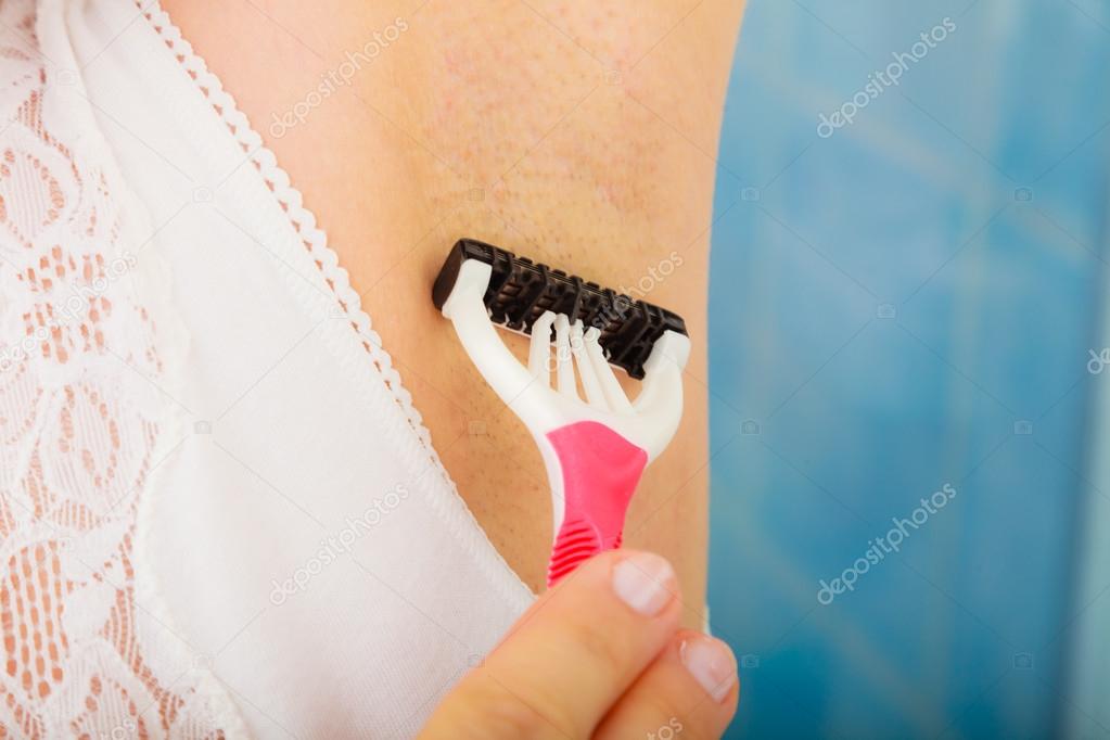 Woman shaving armpit Stock Photo by ©Voyagerix 72088209