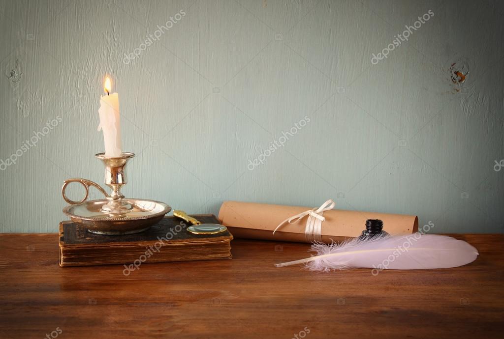 Low key image of white Feather, inkwell and scroll on old wooden table ...