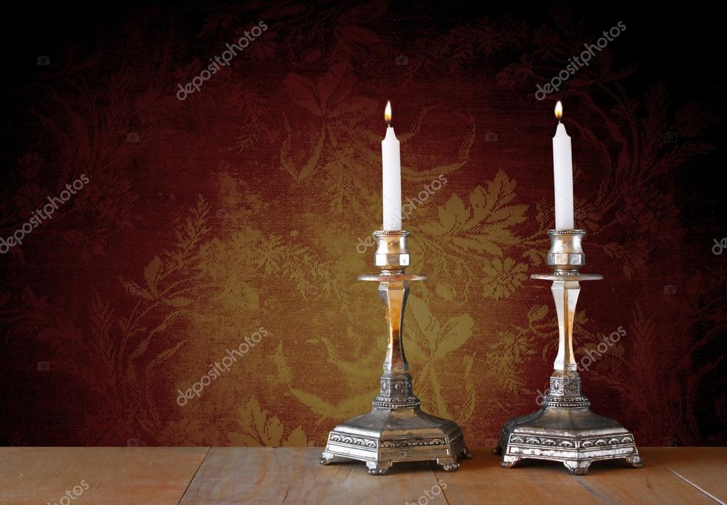 Two candlesticks with burning candles over wooden table and vintage ...