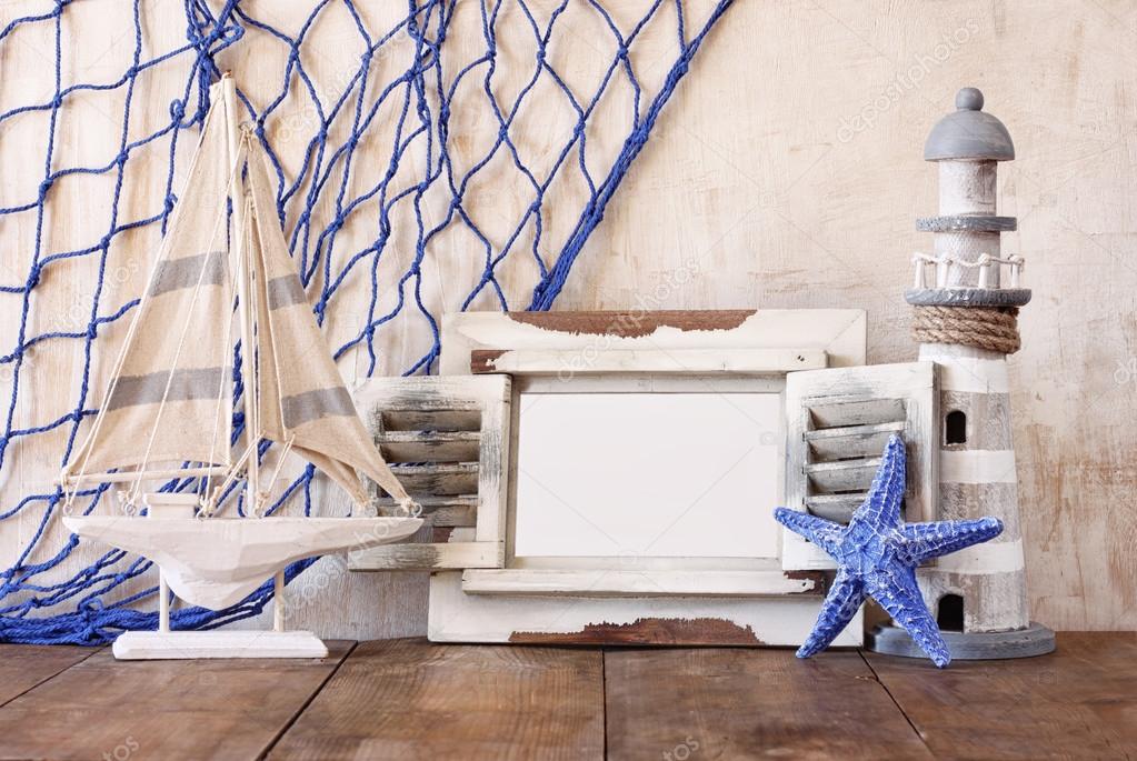 Antiguo marco blanco de madera vintage, faro y velero sobre mesa de ...