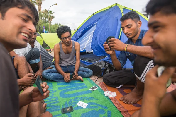 War refugees playing cards near tents - Stock Image - Everypixel
