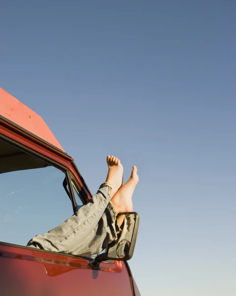 Woman's feet sticking out of car window - Stock Image - Everypixel